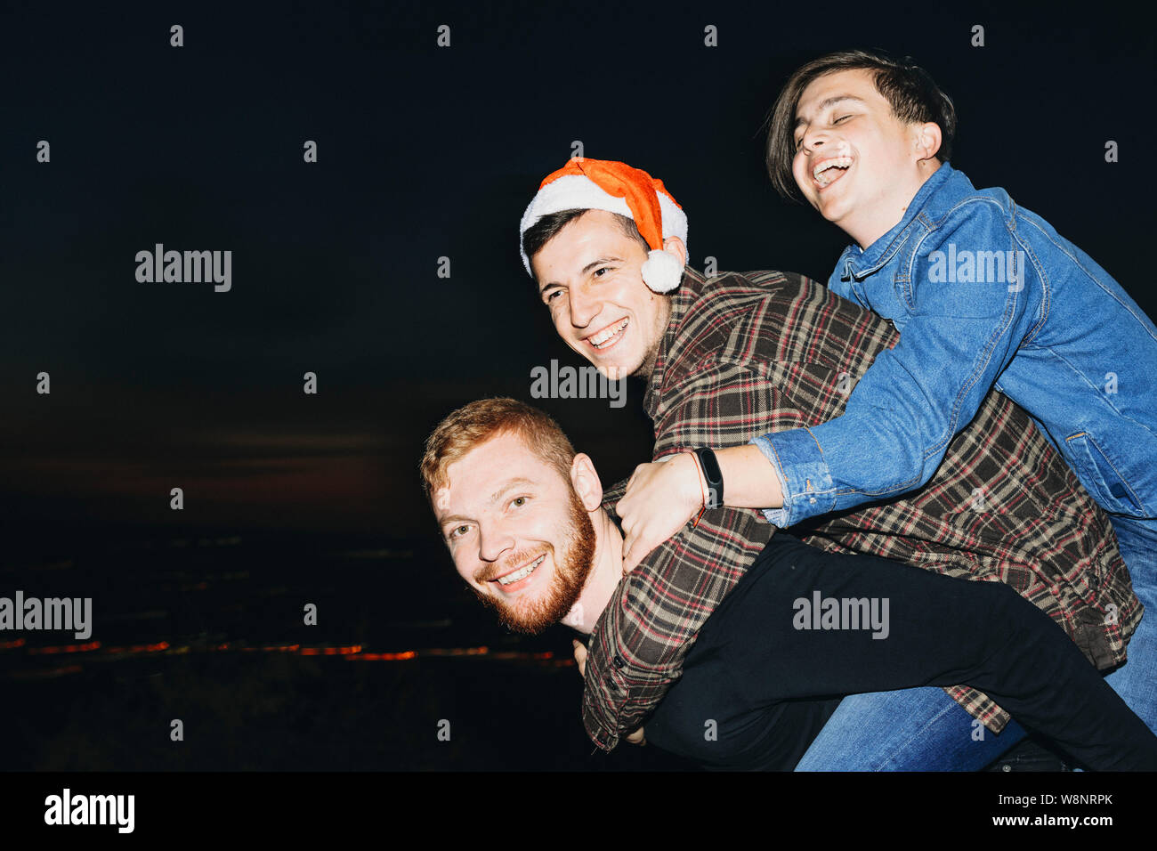 Side view of two excited men laughing and sitting on back of cheerful ...