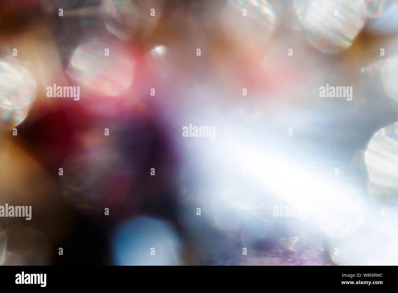 Blurred spots of bright light shimmering around smooth flare on dark ...