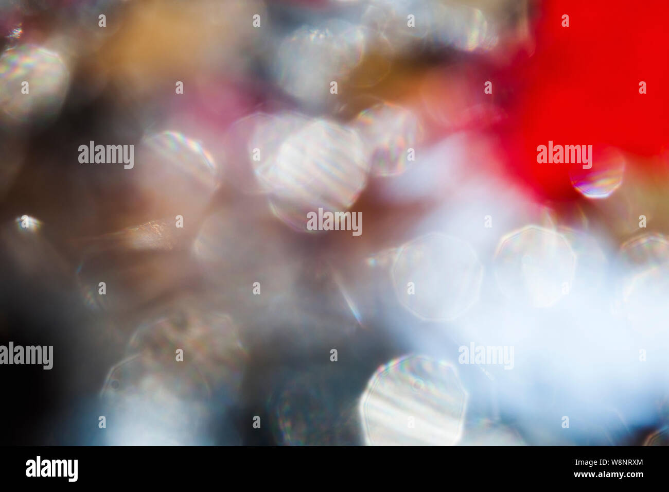 Bright red flash shimmering near smooth specks of light in dark room ...