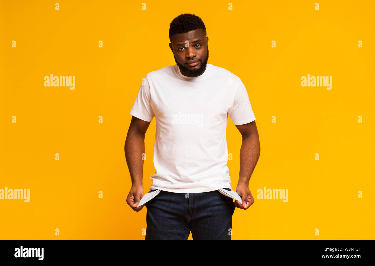 Poor sad african american man showing empty pockets Stock Photo - Alamy