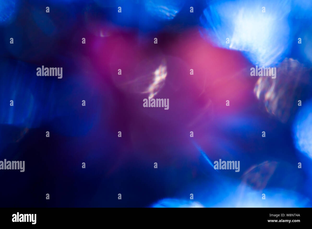 Closeup shot of bright specks of blue light glimmering over pink flare ...