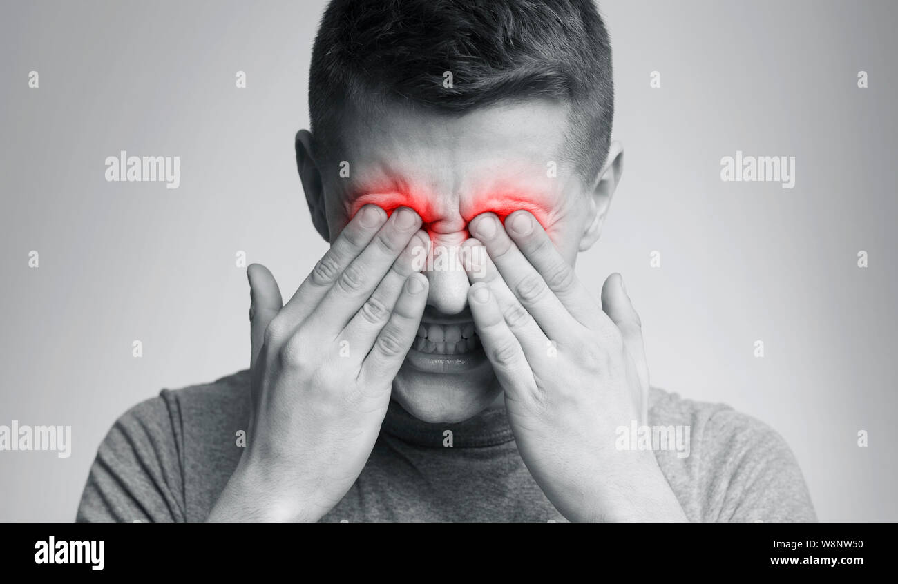 Poor young man has issues with vision, rubbing his eyes Stock Photo - Alamy