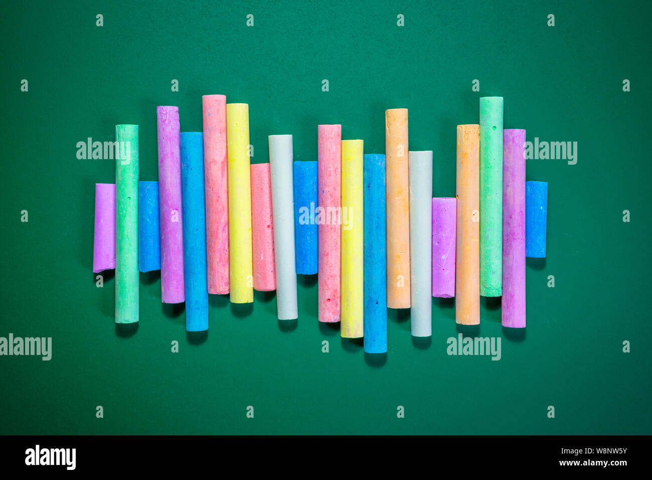 Multicolored chalks on a green chalkboard, back to school concept. Top ...