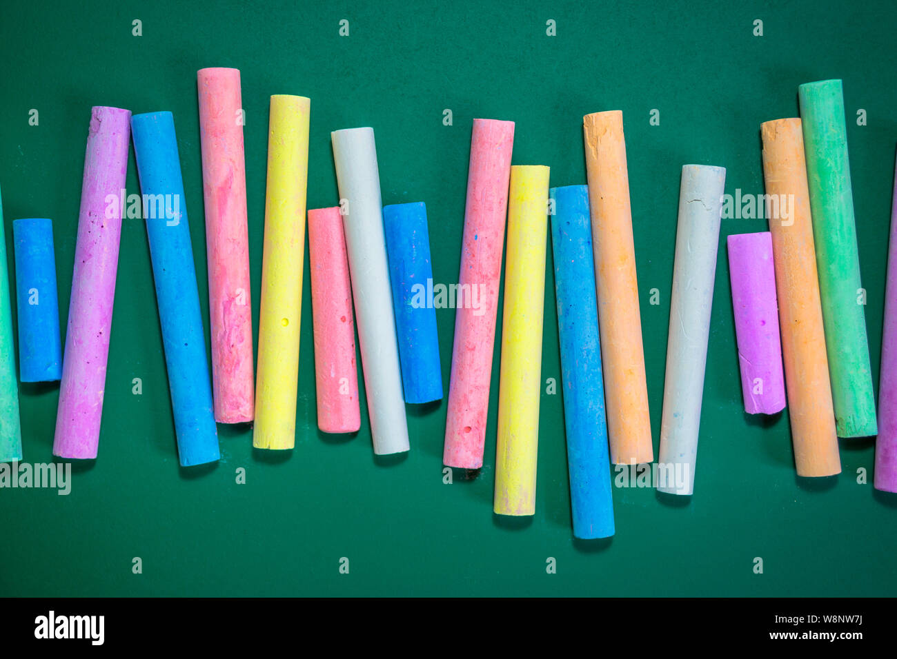 Multicolored chalks on a green chalkboard, back to school concept. Top ...
