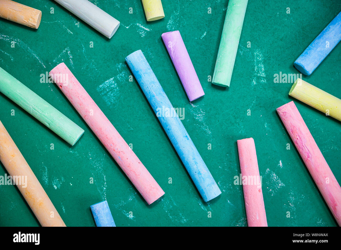 Multicolored chalks scattered on a green chalkboard, back to school ...