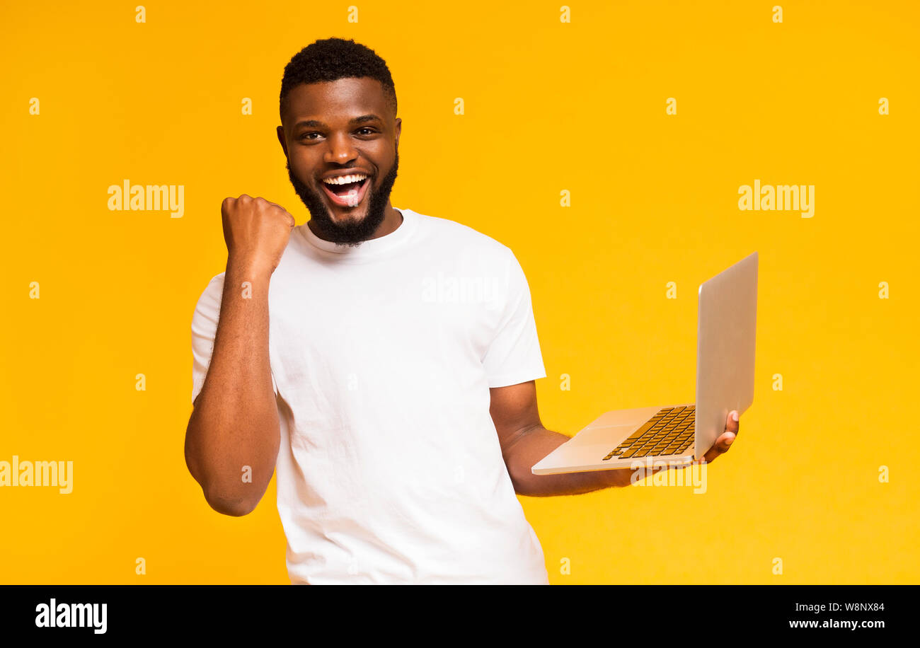 Excited african man celebrating win with laptop Stock Photo - Alamy