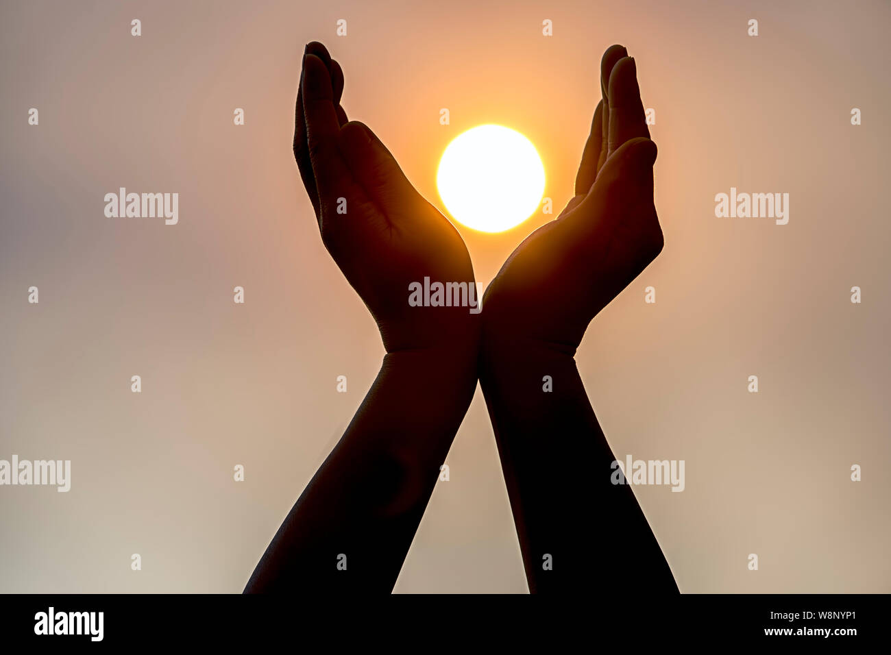 Conceptual image of holding the sun in two hands Stock Photo - Alamy