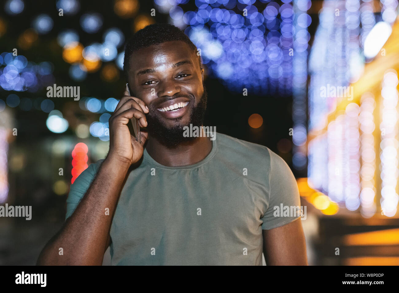 Afro guy talking on phone while walking by night city Stock Photo - Alamy