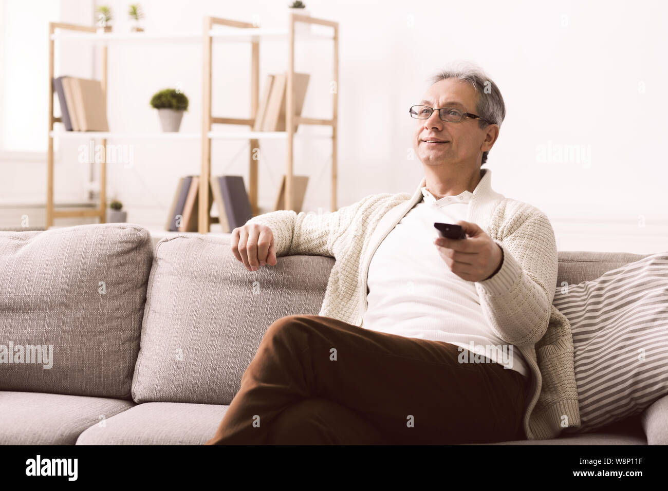 Retired man watching tv with remote control Stock Photo - Alamy