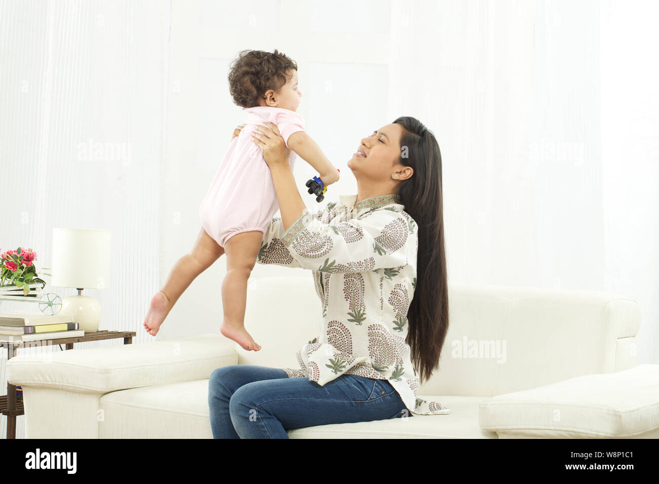 Mother suffering from lower back pain while picking up baby Stock Photo ...