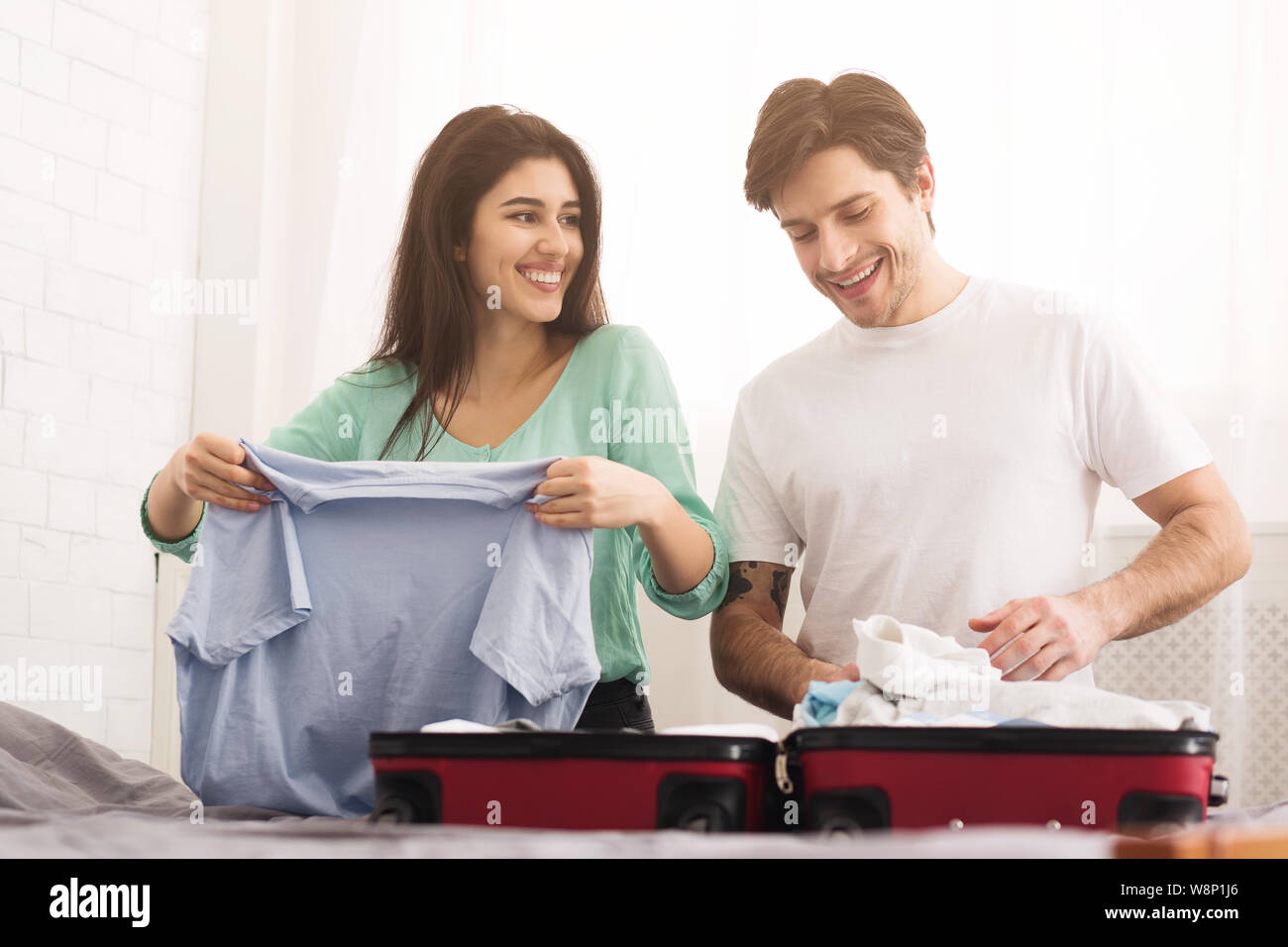 Happy couple preparing for honeymoon, folding clothes Stock Photo - Alamy