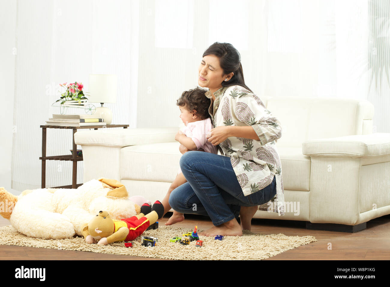 Mother carrying baby and suffering from lower back pain Stock Photo - Alamy