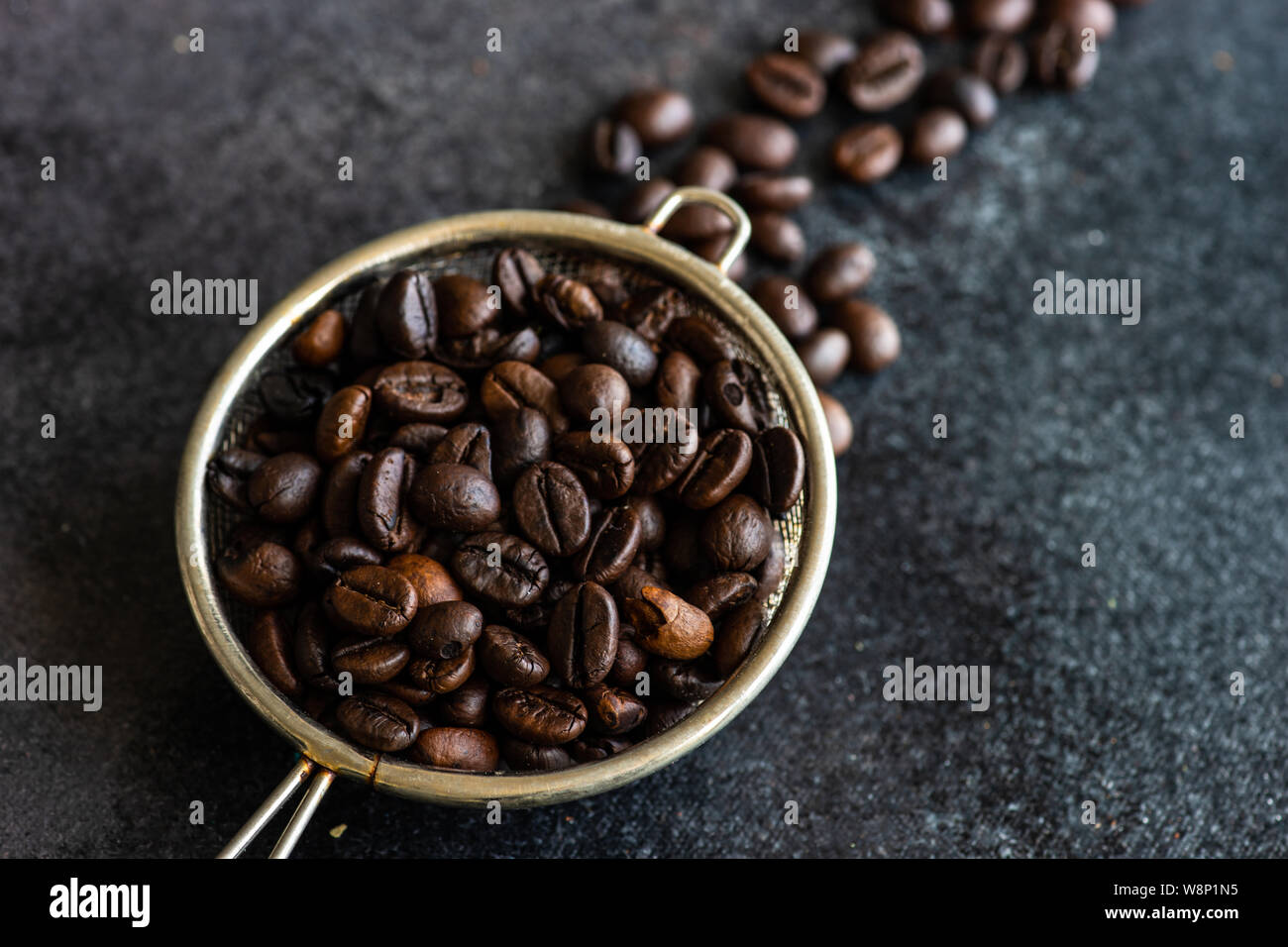 Strained full of coffee beans on dark stone background with copy space ...