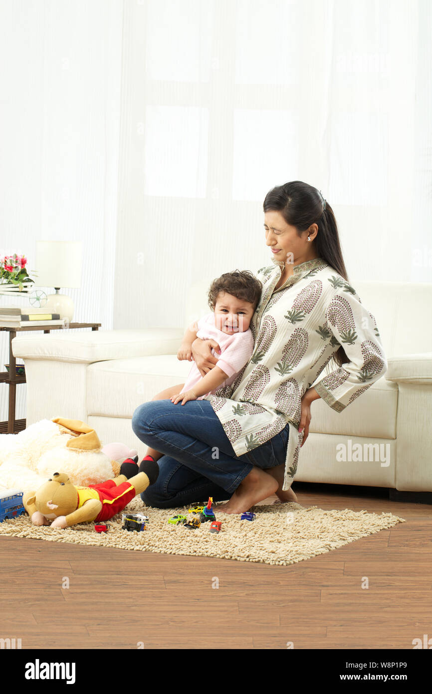 Mother carrying baby and suffering from lower back pain Stock Photo - Alamy