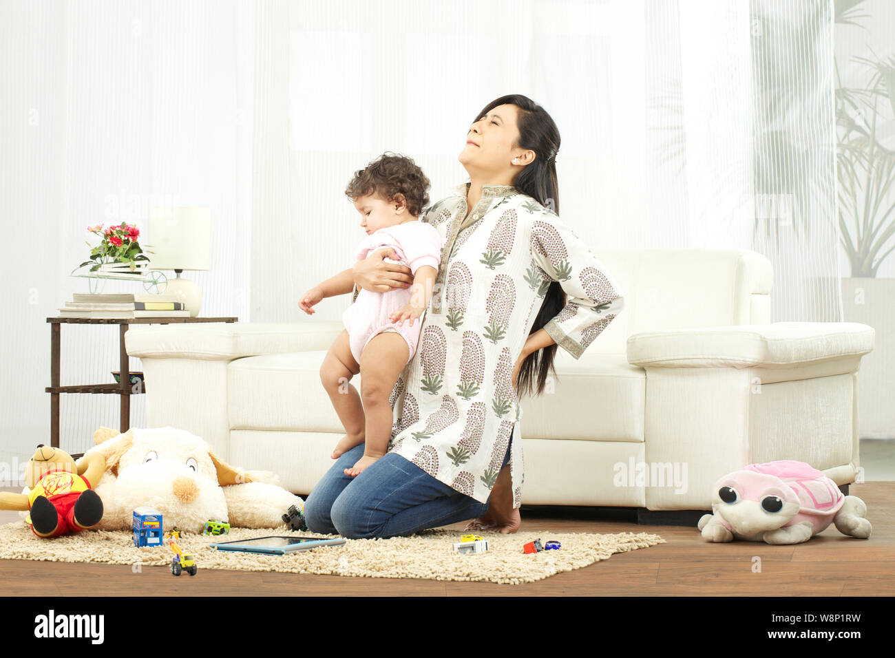 Mother carrying baby and suffering from lower back pain Stock Photo - Alamy