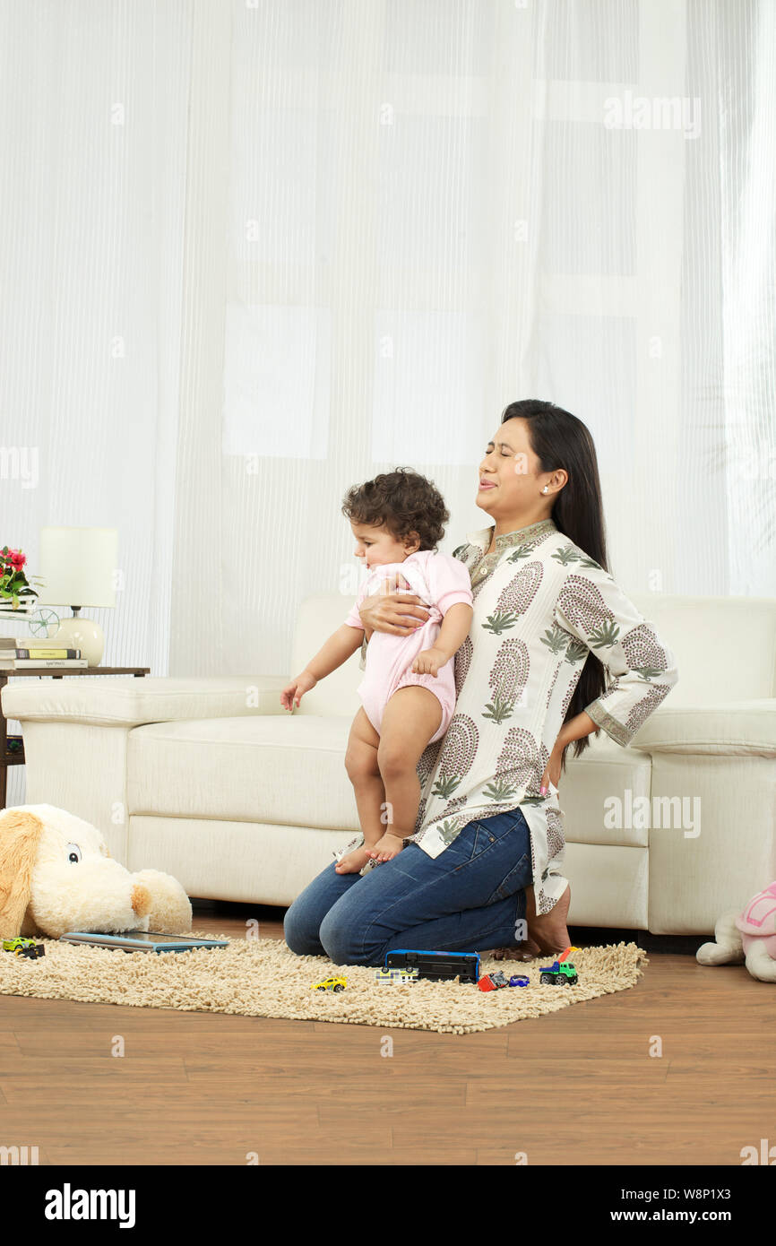 Mother carrying baby and suffering from lower back pain Stock Photo - Alamy