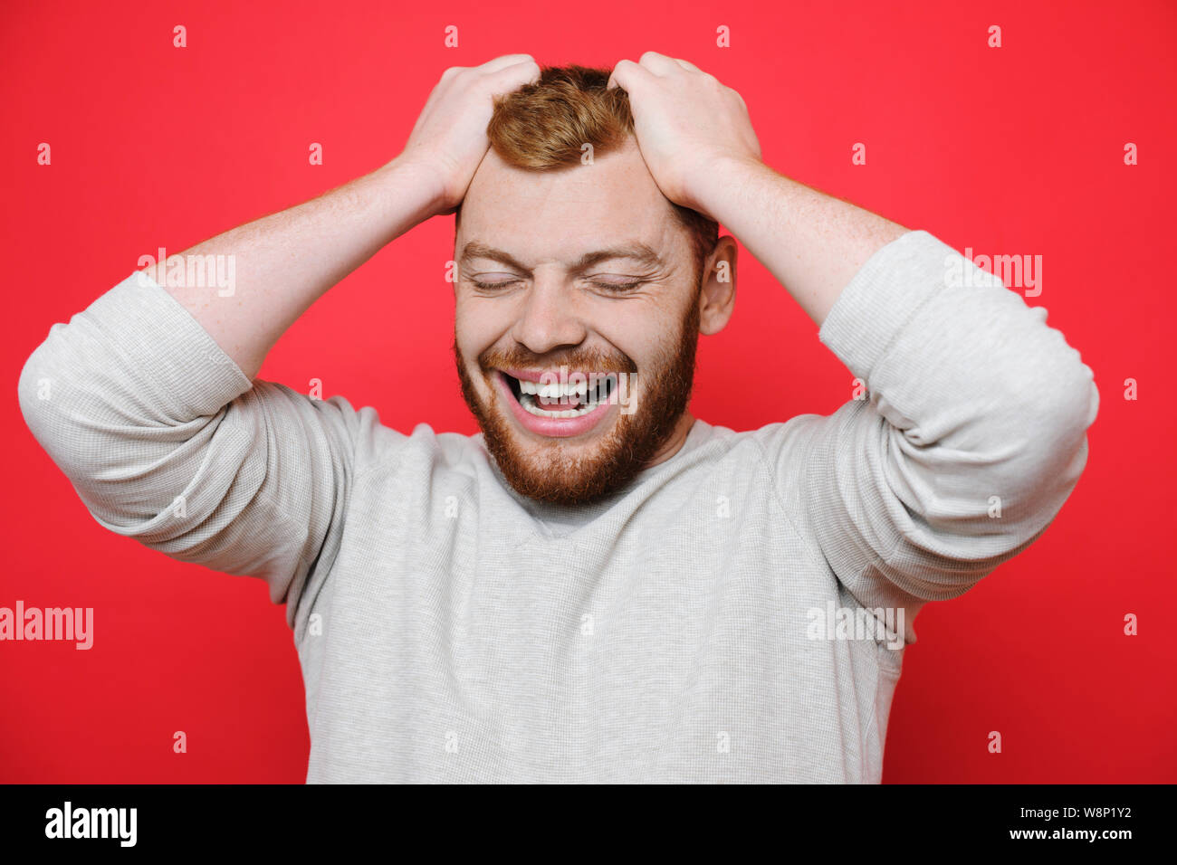 Bearded guy tearing hair and crying while standing on bright red ...