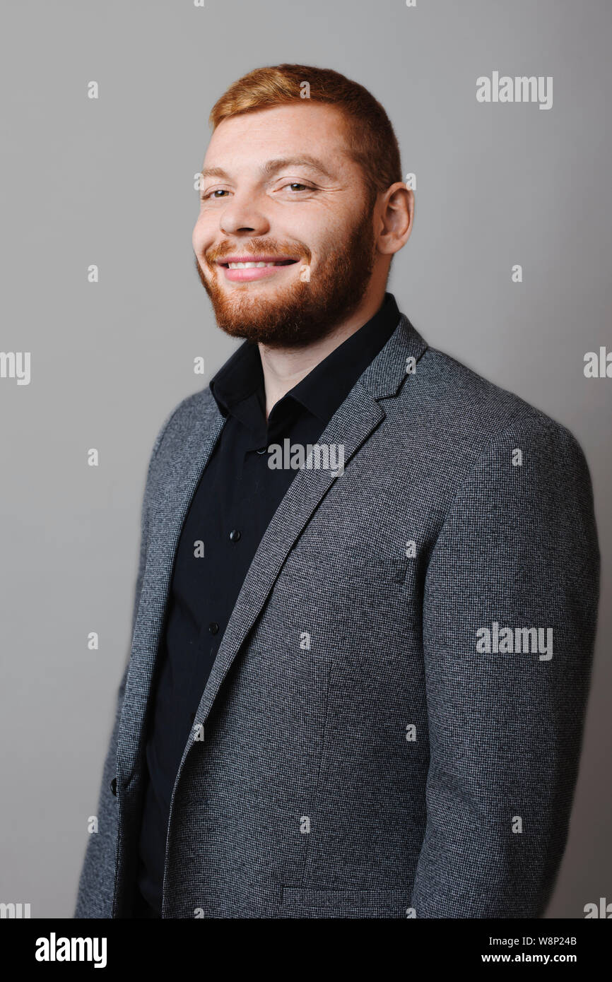 Side view of handsome red-bearded guy in elegant suit cheerfully ...