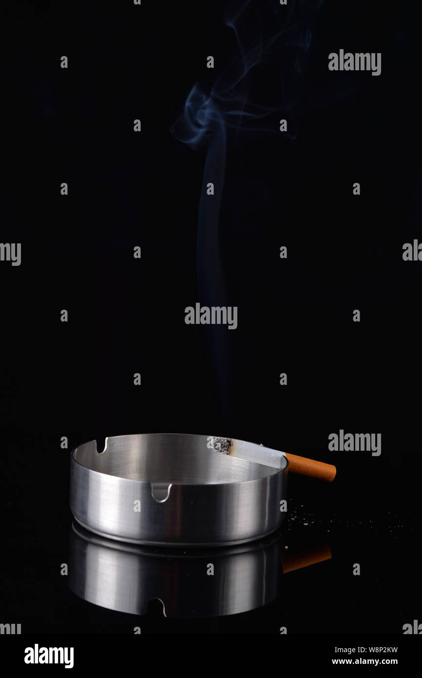 Smoke rising from a cigarette in an ashtray Stock Photo - Alamy
