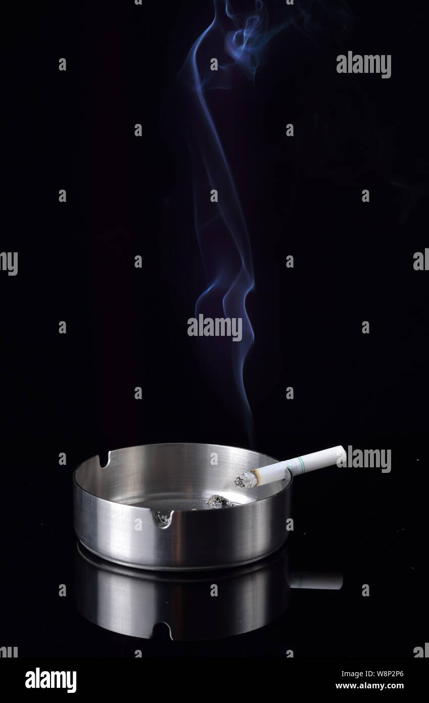 Smoke rising from a cigarette in an ashtray Stock Photo - Alamy