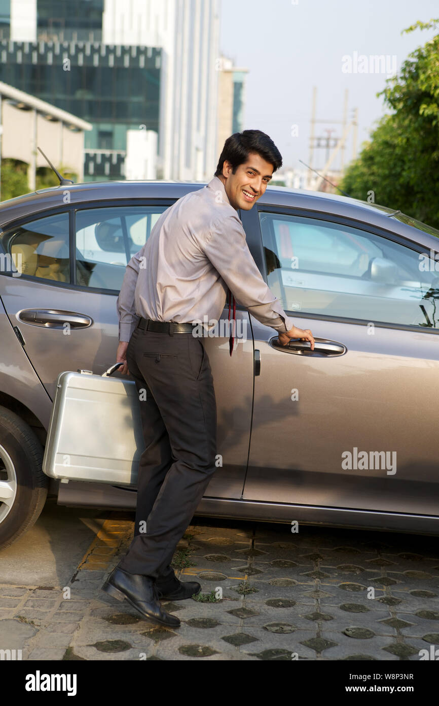 Businessman opening car door and smiling Stock Photo - Alamy