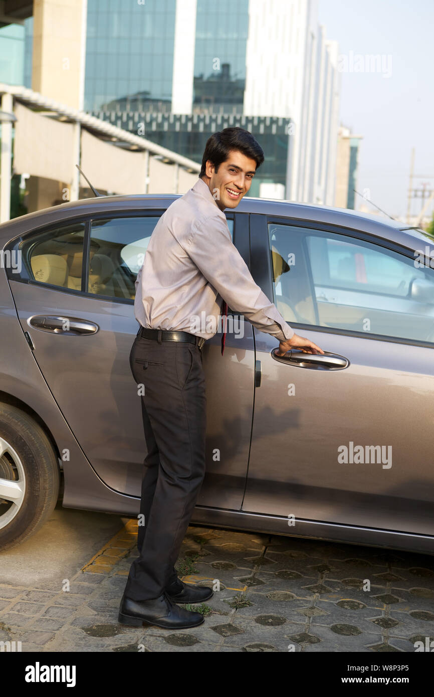Businessman opening car door and smiling Stock Photo - Alamy