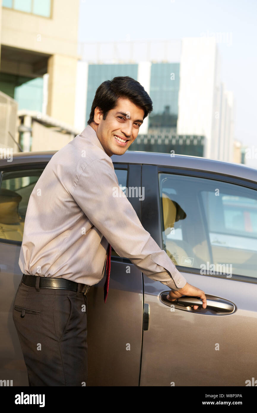 Businessman opening car door and smiling Stock Photo - Alamy