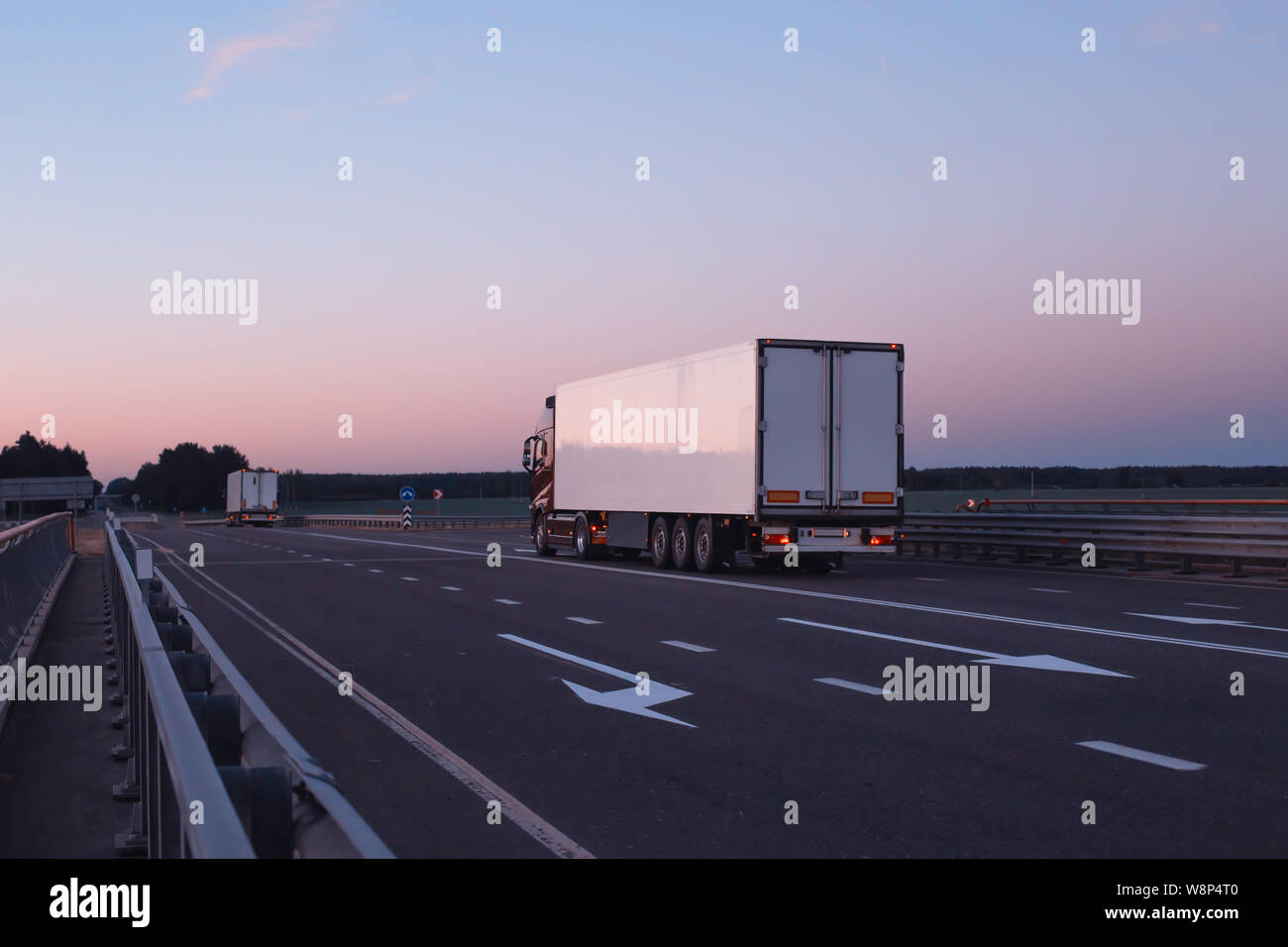 A convoy of trucks trucks transports the cargo in the evening on the ...