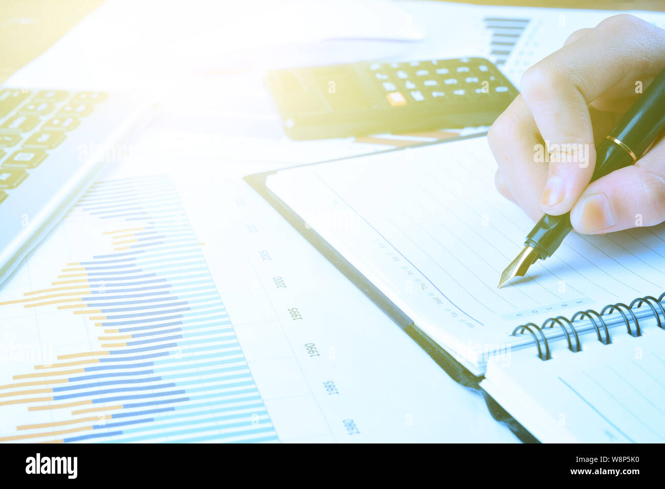 Hand writing on blank notebook with graph, chart, keyboard, mouse and ...