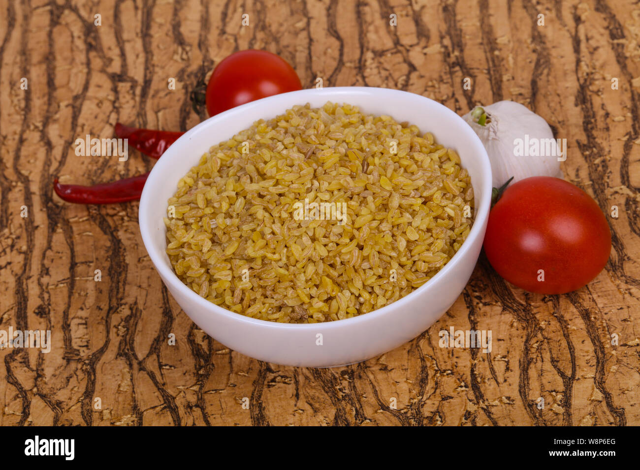 Raw golden bulgur in the bowl with tomatoes and garlic Stock Photo - Alamy