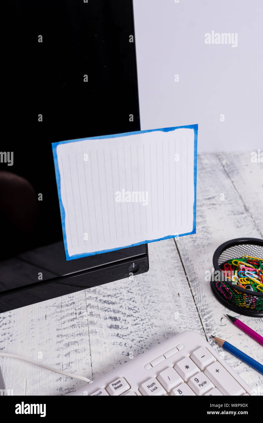 Note paper taped to black computer screen near keyboard and stationary ...