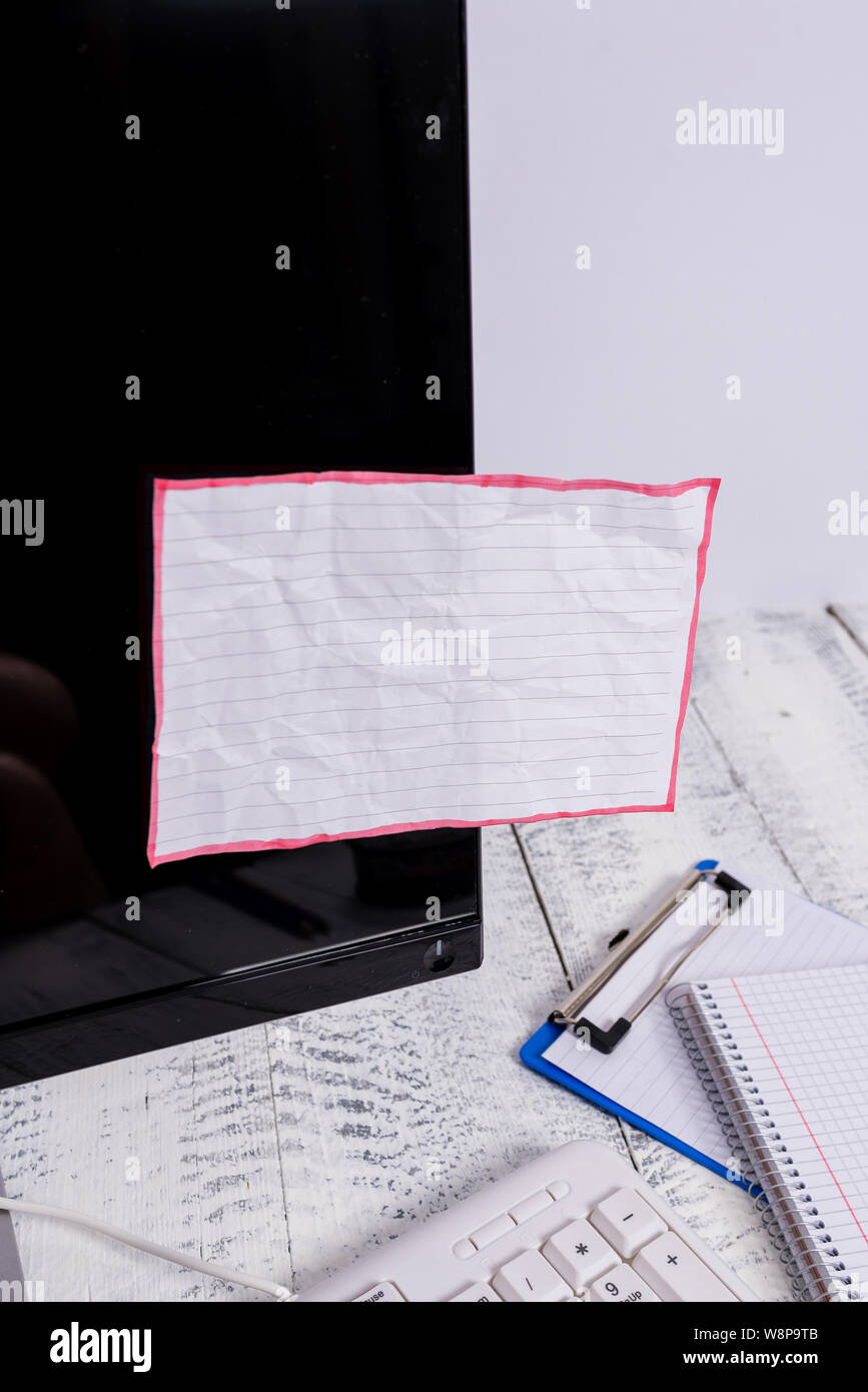 Note paper taped to black computer screen near keyboard and stationary ...
