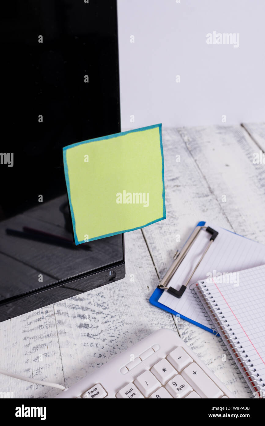 Note paper taped to black computer screen near keyboard and stationary ...