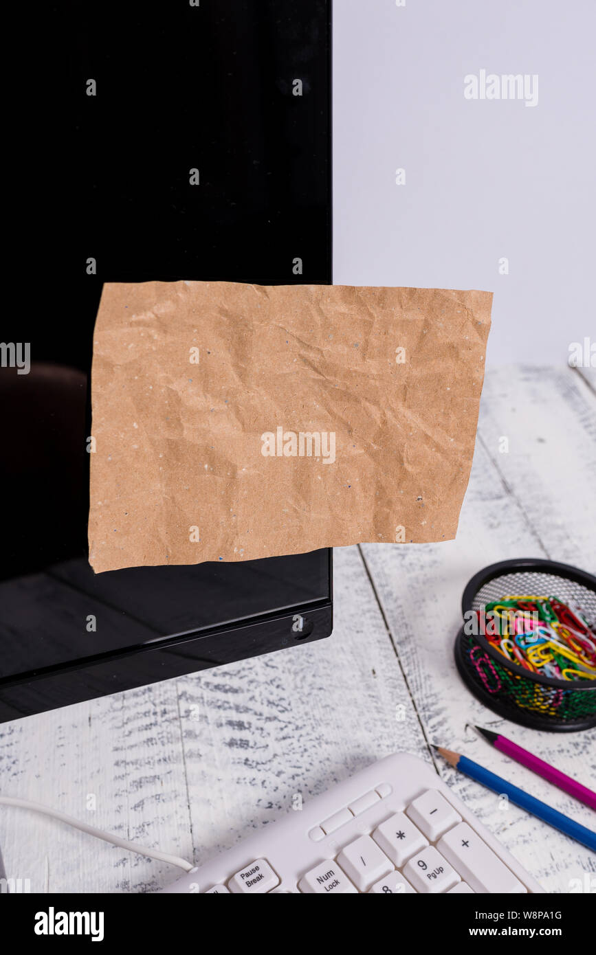 Note paper taped to black computer screen near keyboard and stationary ...