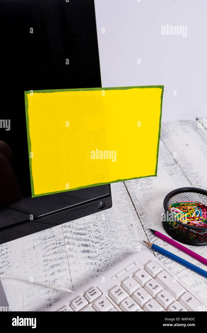 Note paper taped to black computer screen near keyboard and stationary ...