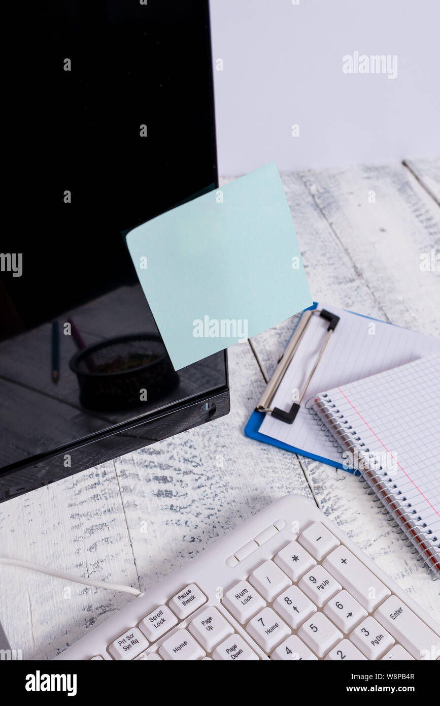 Note paper taped to black computer screen near keyboard and stationary ...