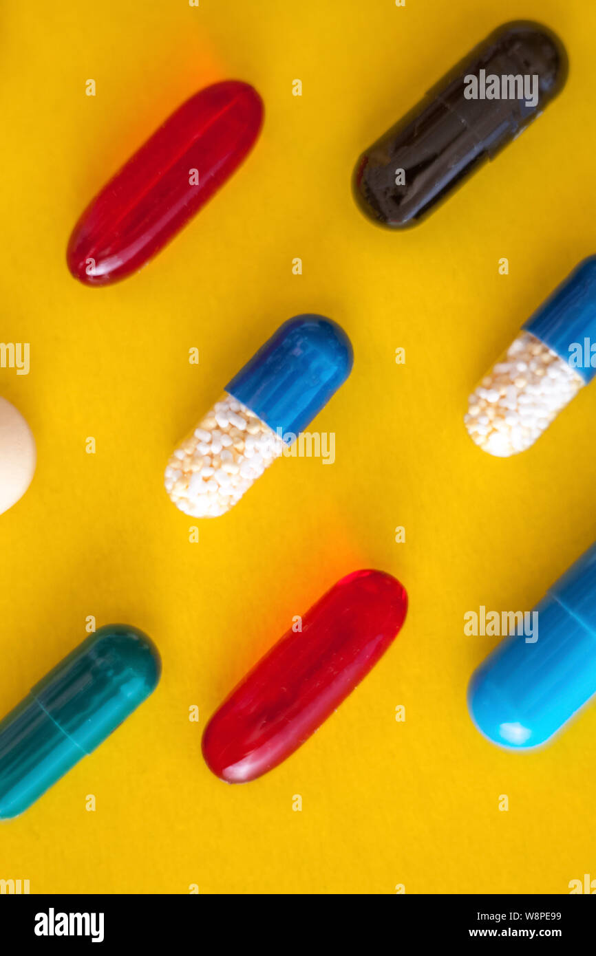 scattered a variety of multi-colored pills in a yellow-orange ...