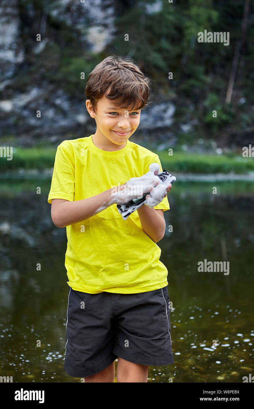 Little boy is destroying cellular phone while washing it in river with ...