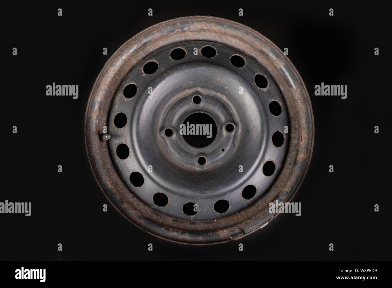 Old black metal rim on a workbench. Rusty car accessories. Dark ...