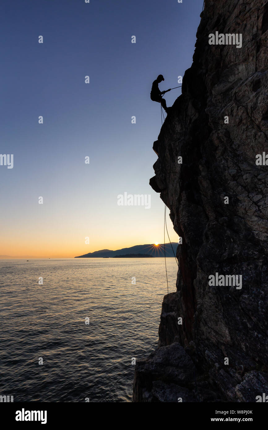Silhouette of a Unrecognizable man rappelling down a steep cliff on the ...