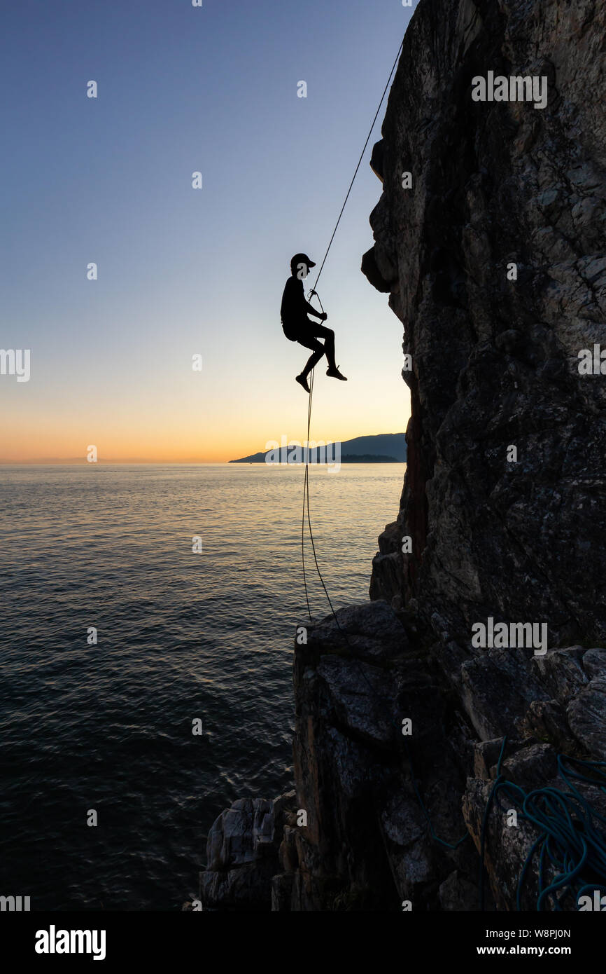 Silhouette of a Unrecognizable man rappelling down a steep cliff on the ...