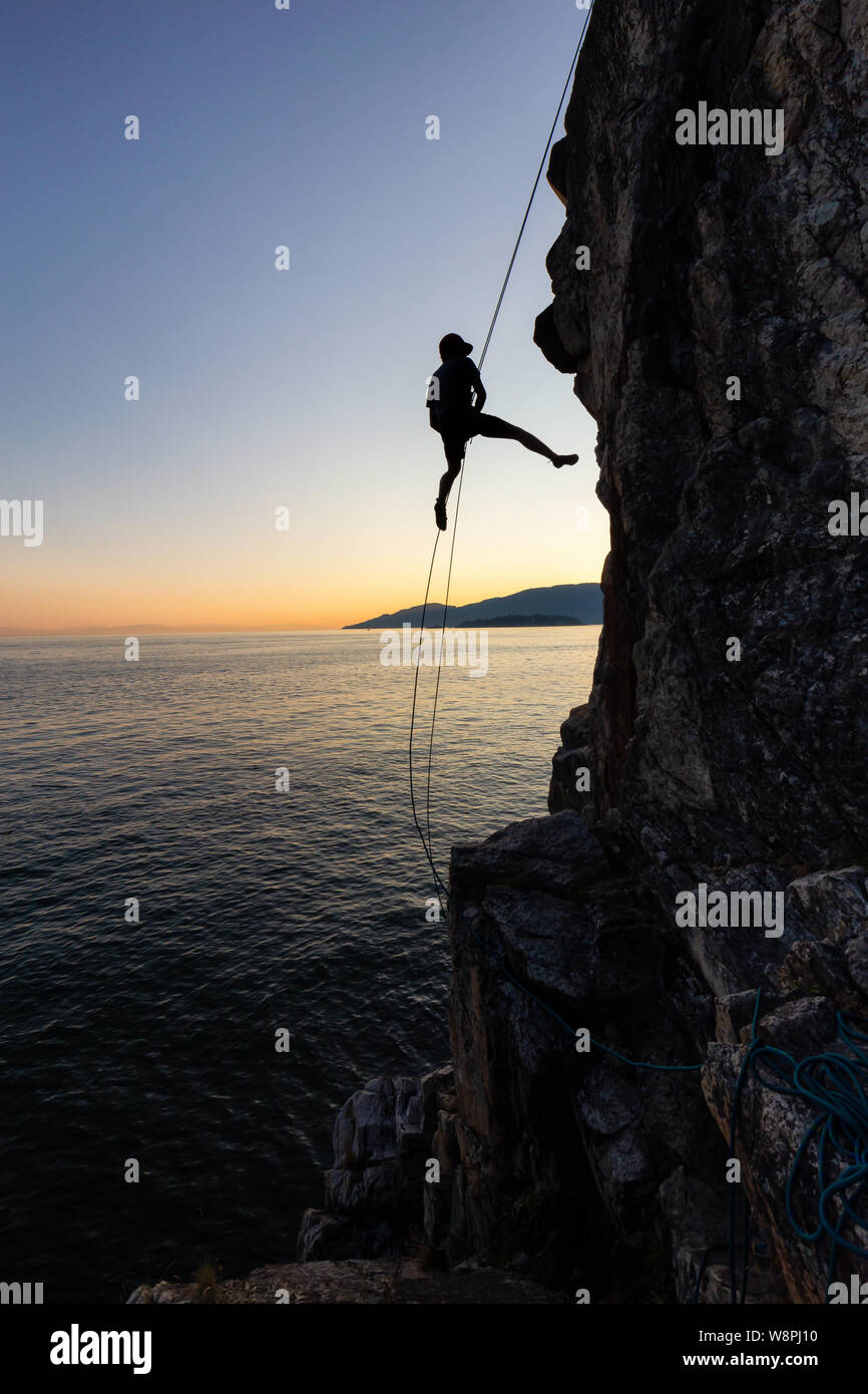 Silhouette of a Unrecognizable man rappelling down a steep cliff on the ...
