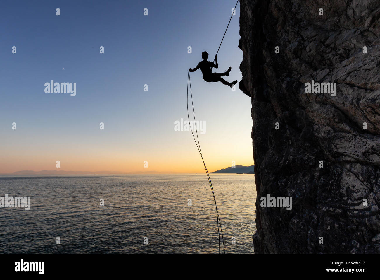 Silhouette of a Unrecognizable man rappelling down a steep cliff on the ...