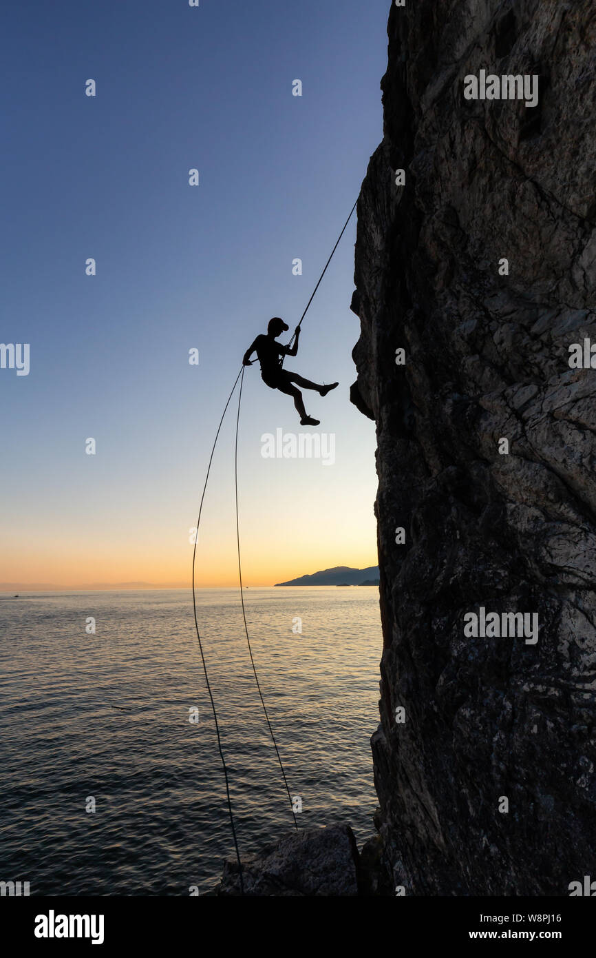 Silhouette of a Unrecognizable man rappelling down a steep cliff on the ...
