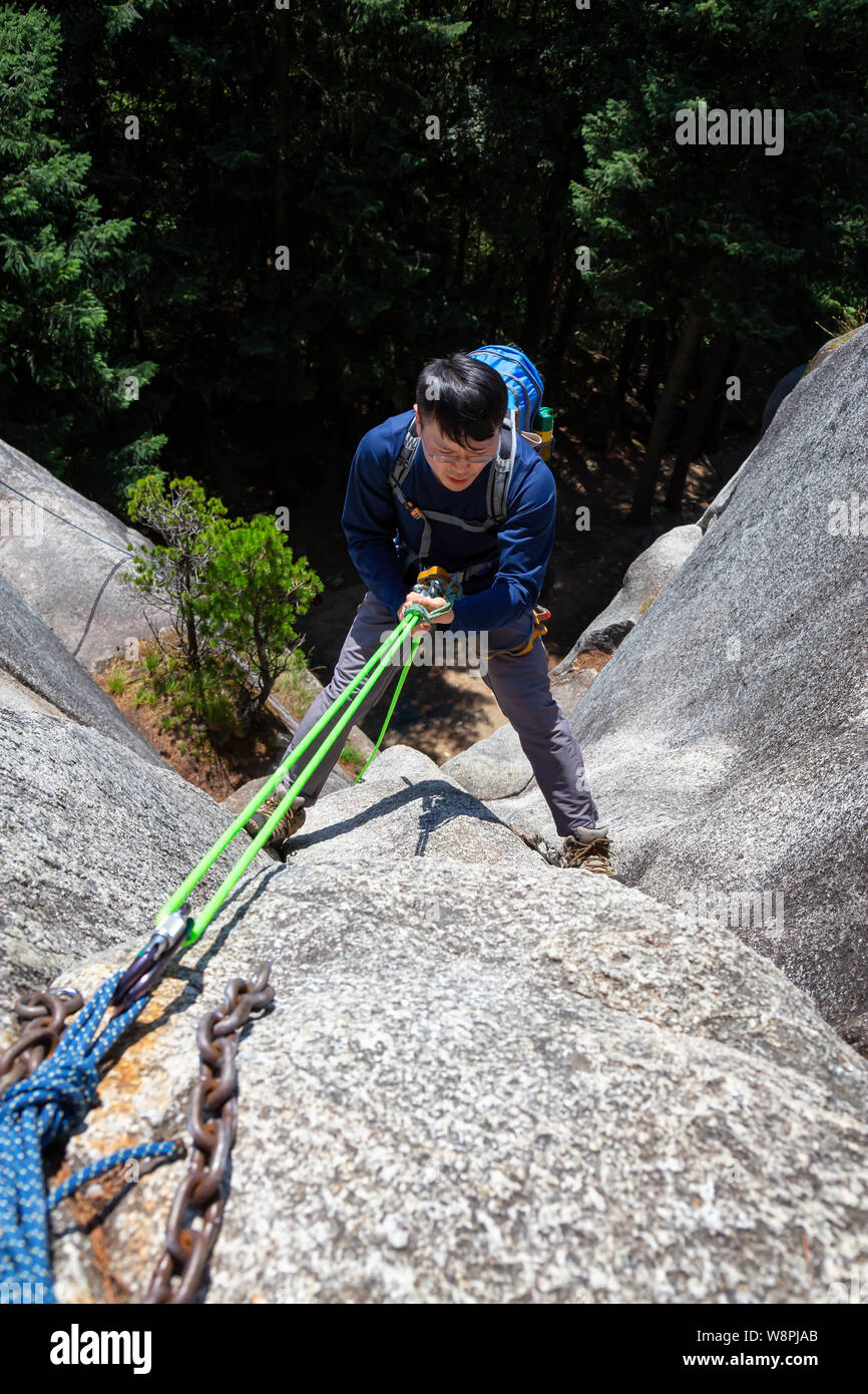 Rock Climber is Rappeling down a steep cliff during a sunny summer day ...