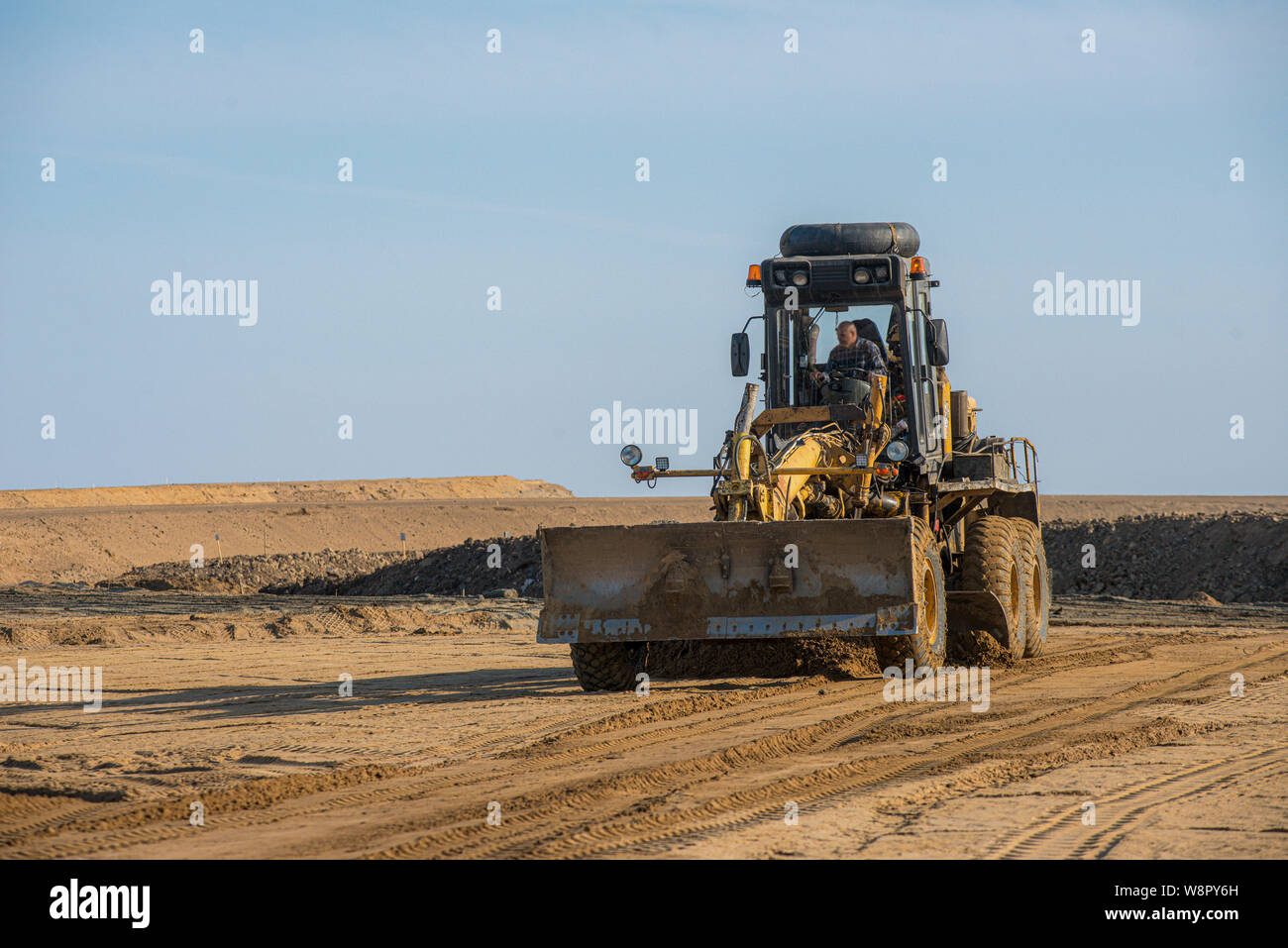 Grader leveling gravel on road construction site Stock Photo - Alamy