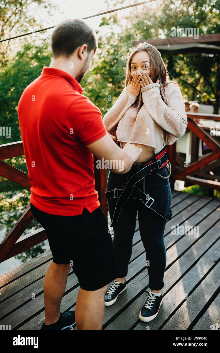Young pretending scared girl wearing safety harness with help of worker ...