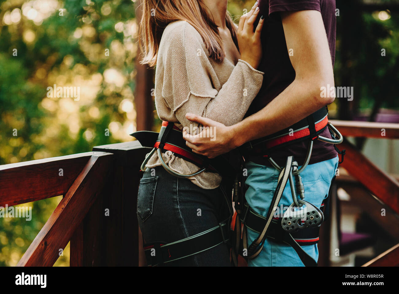 Faceless side view of couple wearing harnesses for riding zip line and ...