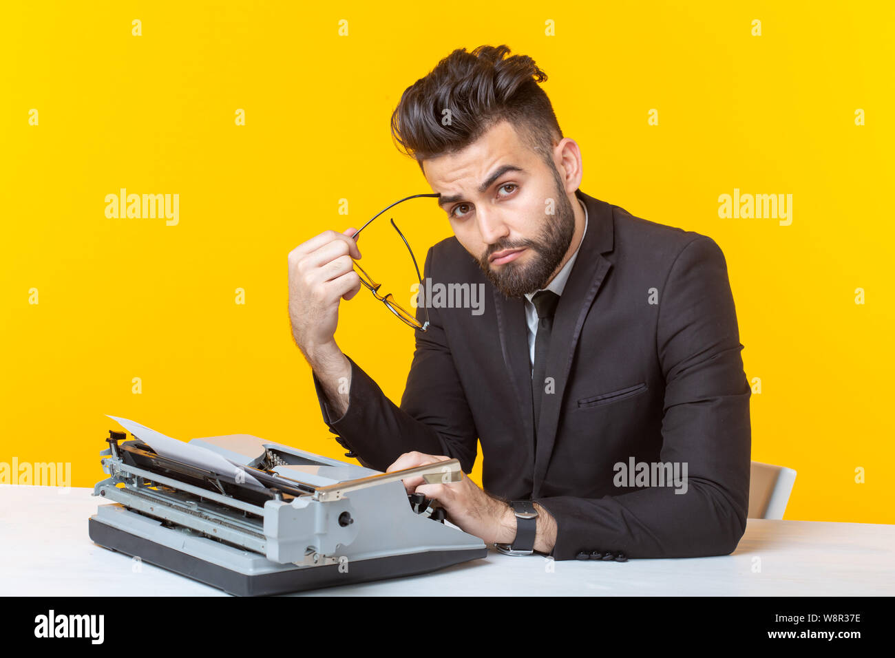 Young pensive tired business man or manager types a document on a ...