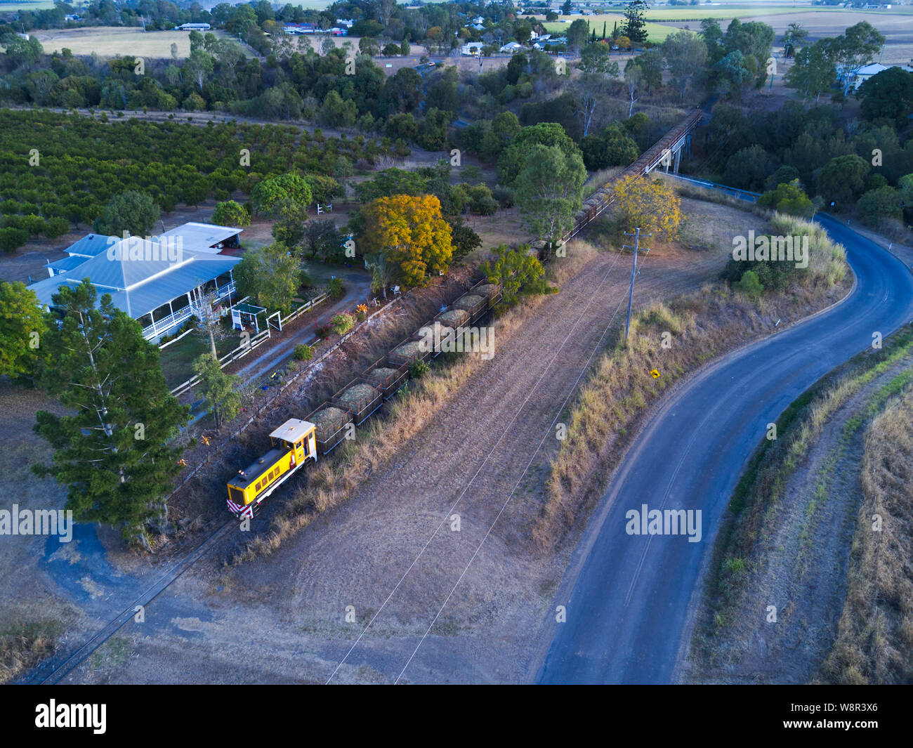Aerial of a Sugar Cane Train passing a traditional Queenslander style ...